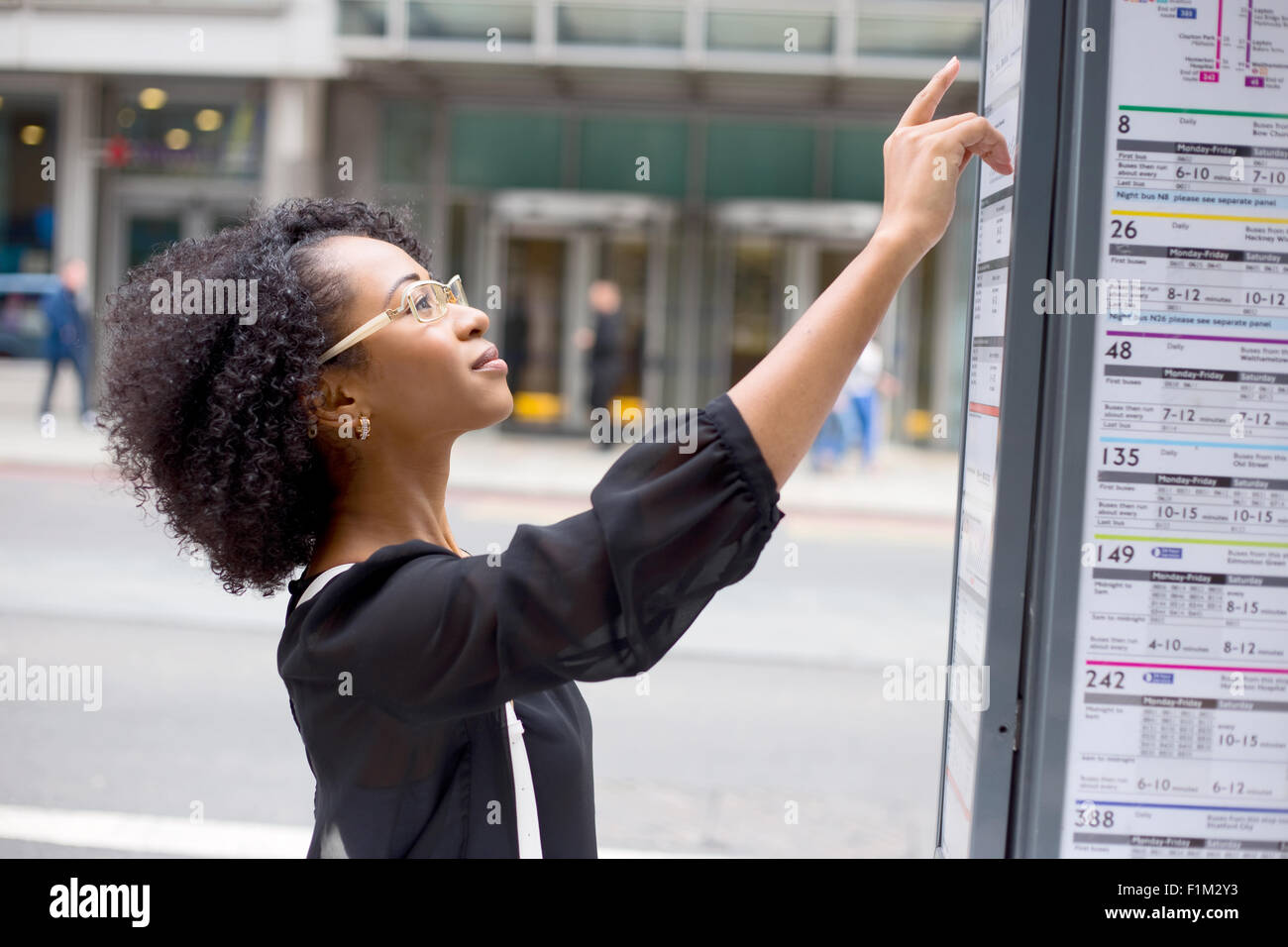 young woman checking the bus timetable in the street Stock Photo - Alamy
