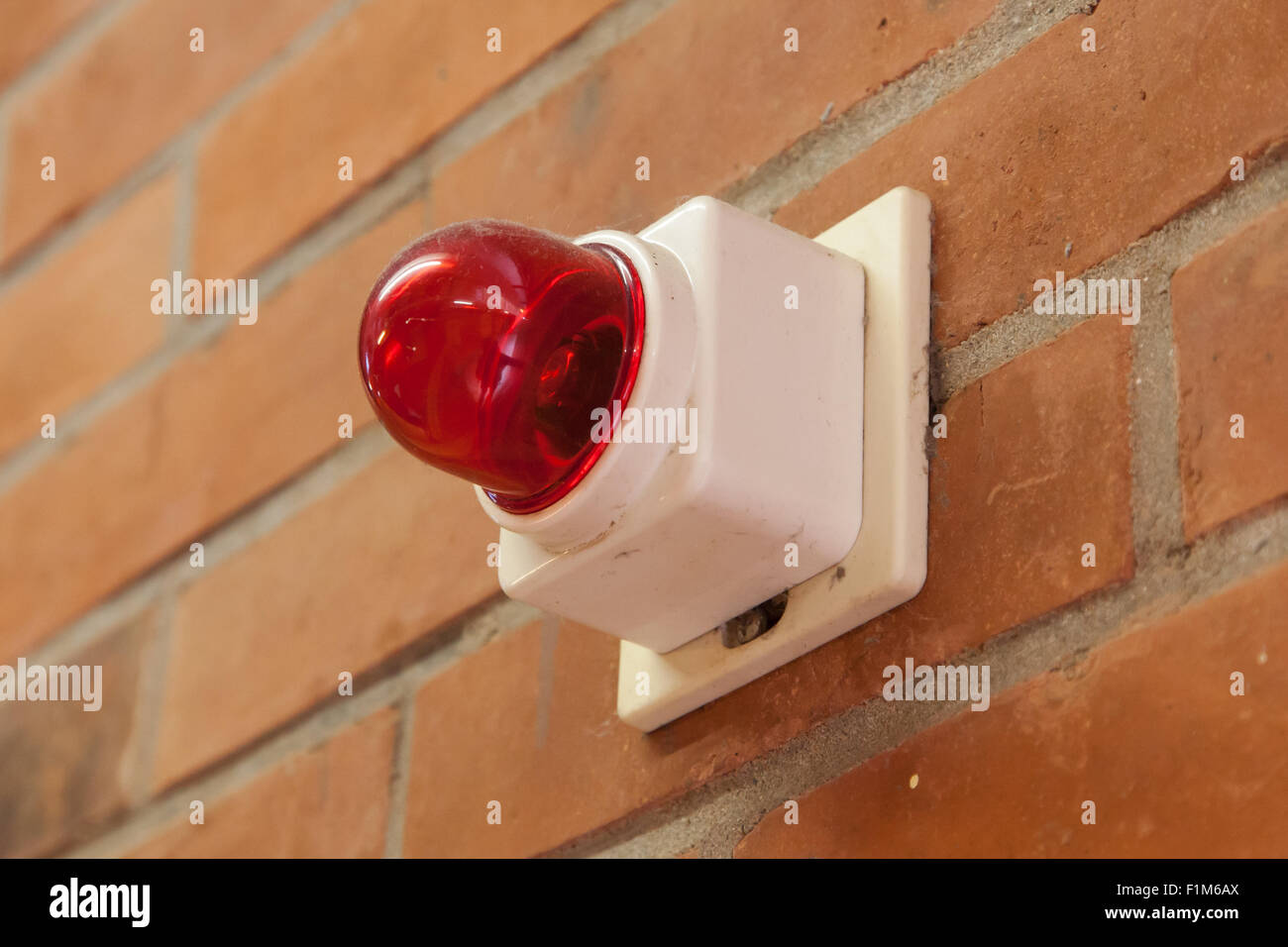 Red emergency light on a brick wall, selective focus Stock Photo - Alamy