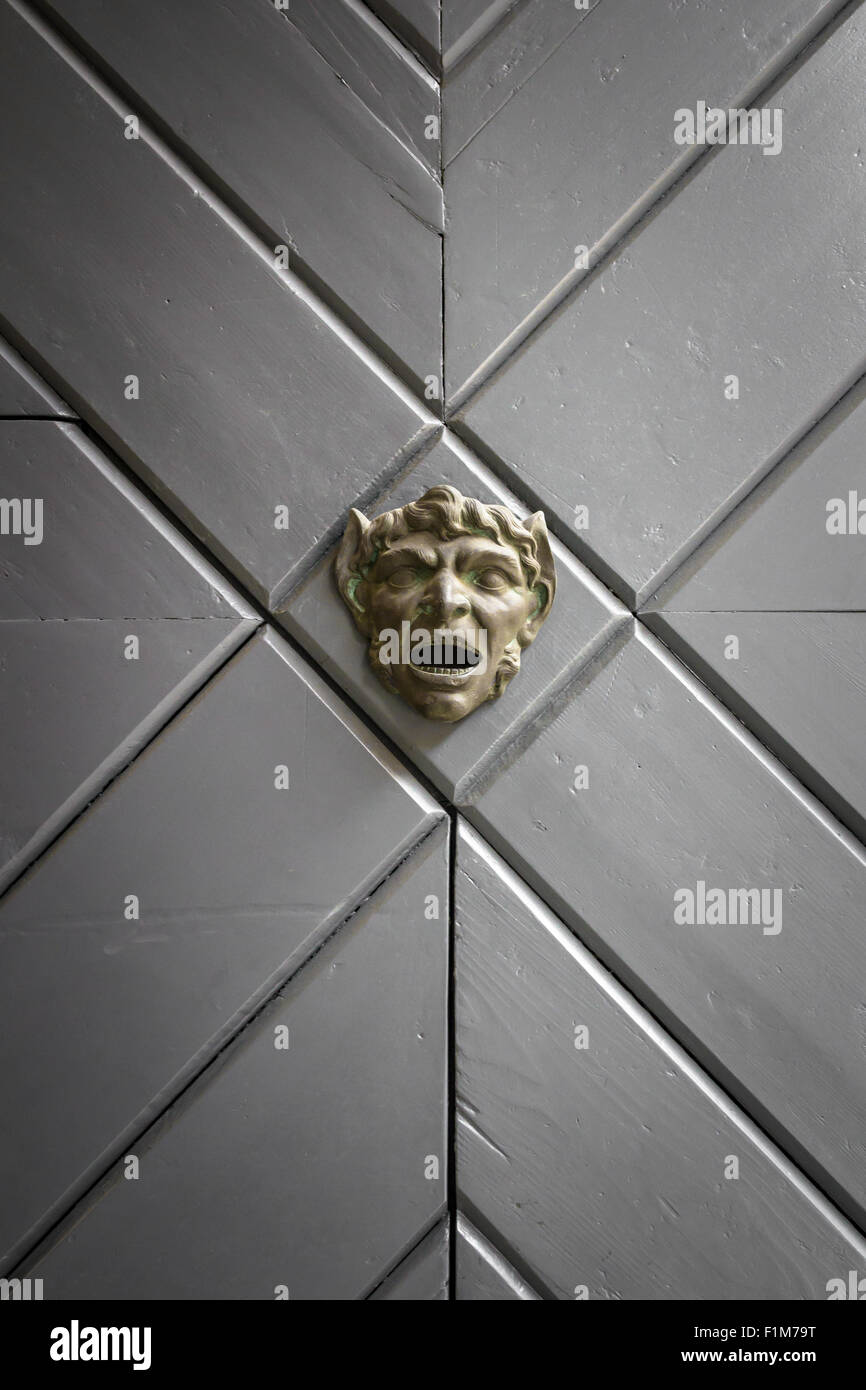 Front view of a door decorated with a face sculpted in bronze Stock ...