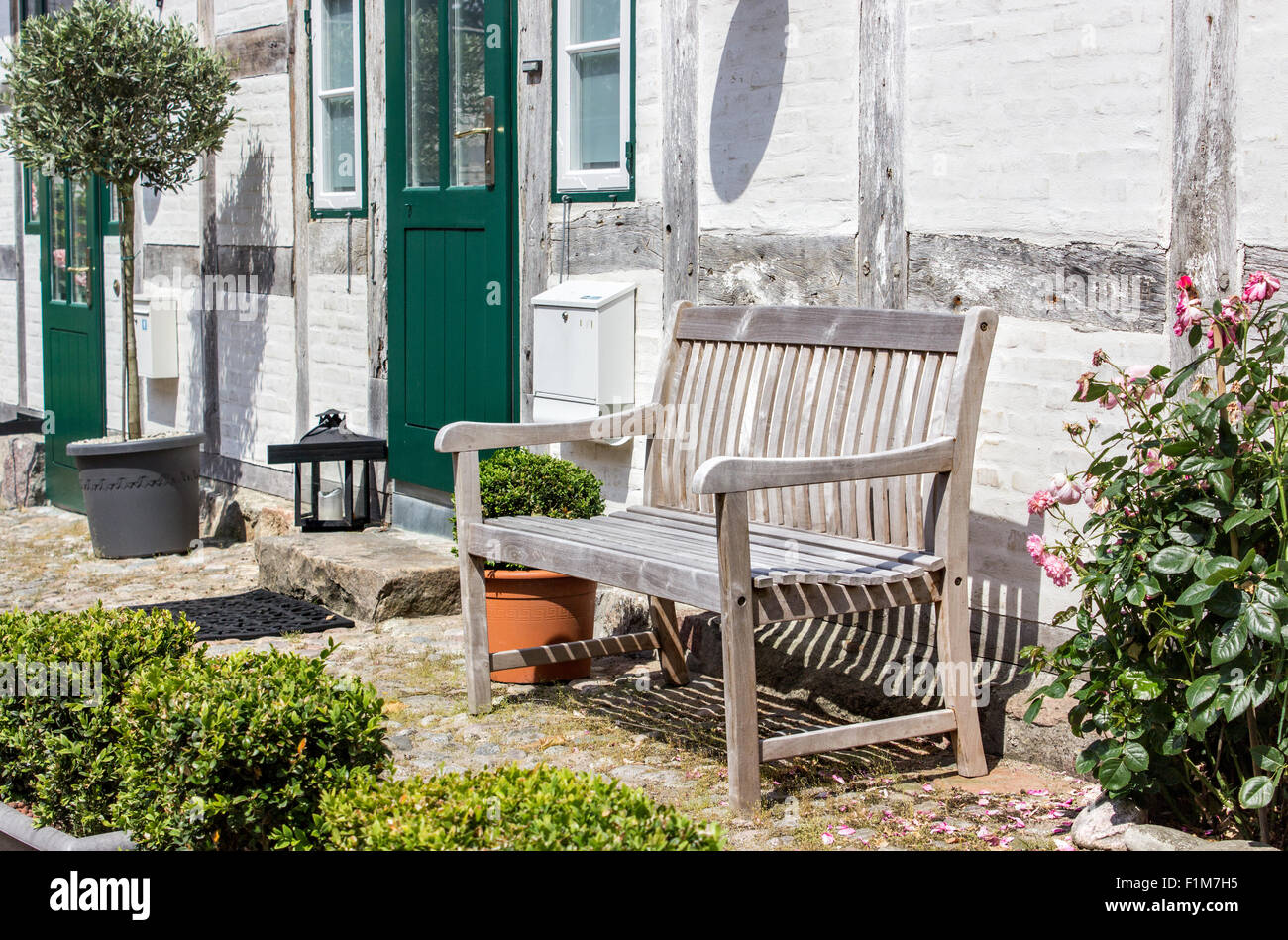 A wooden bench is in front of a residential house Stock Photo - Alamy