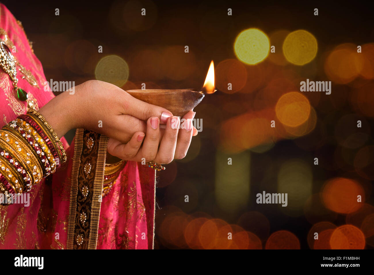Close up Indian woman in traditional sari lighting oil lamp and ...