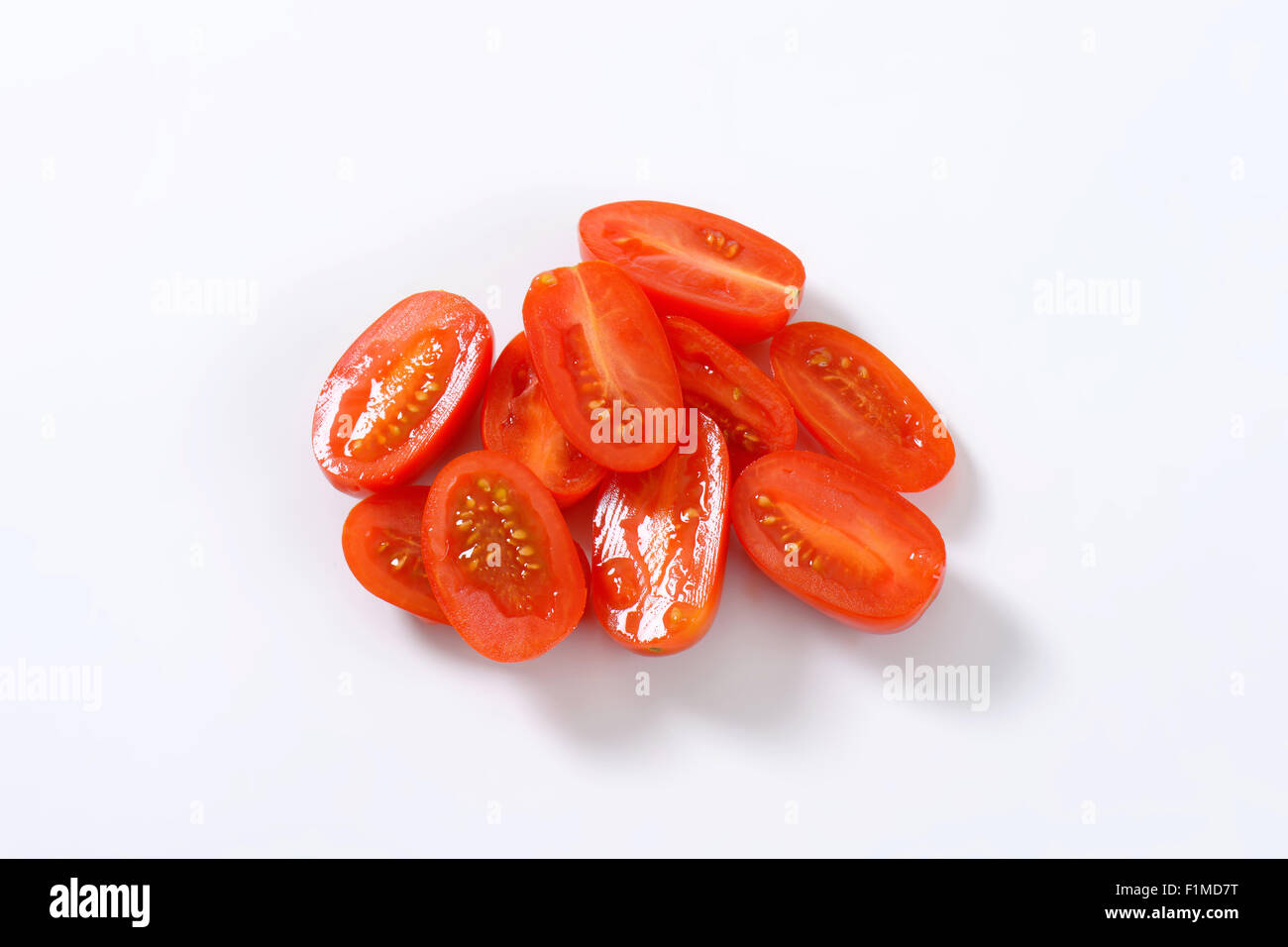 heap of halved cherry tomatoes on white background Stock Photo - Alamy