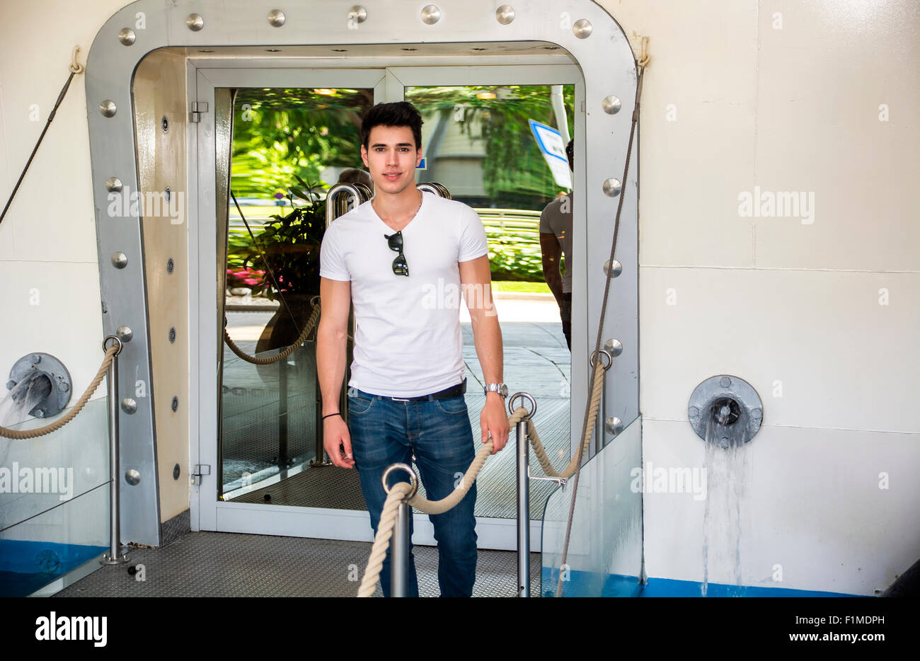 Handsome trendy male passenger on a ship, standing on the gangway ...