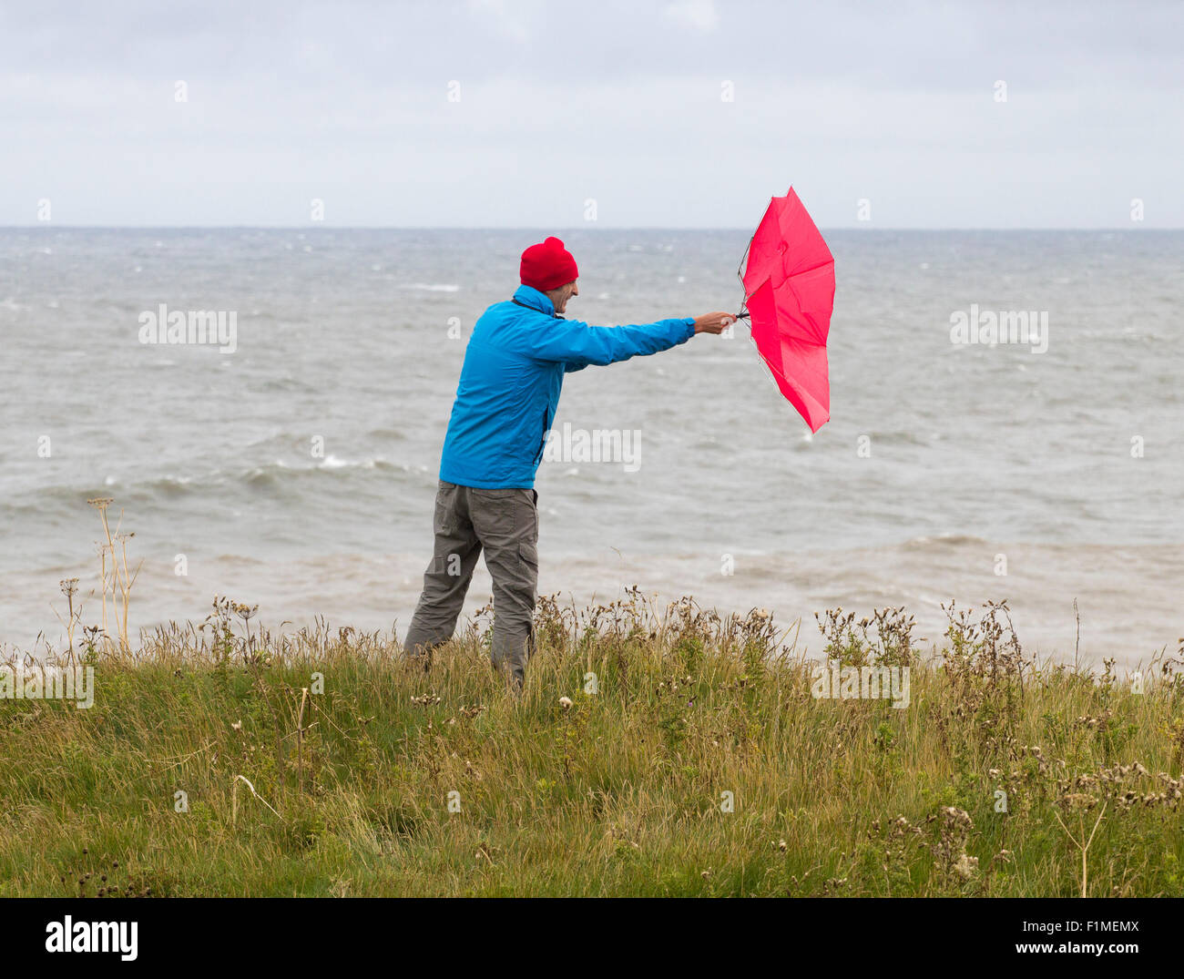 Man with red umbrella on windy/stormy day. UK Stock Photo - Alamy