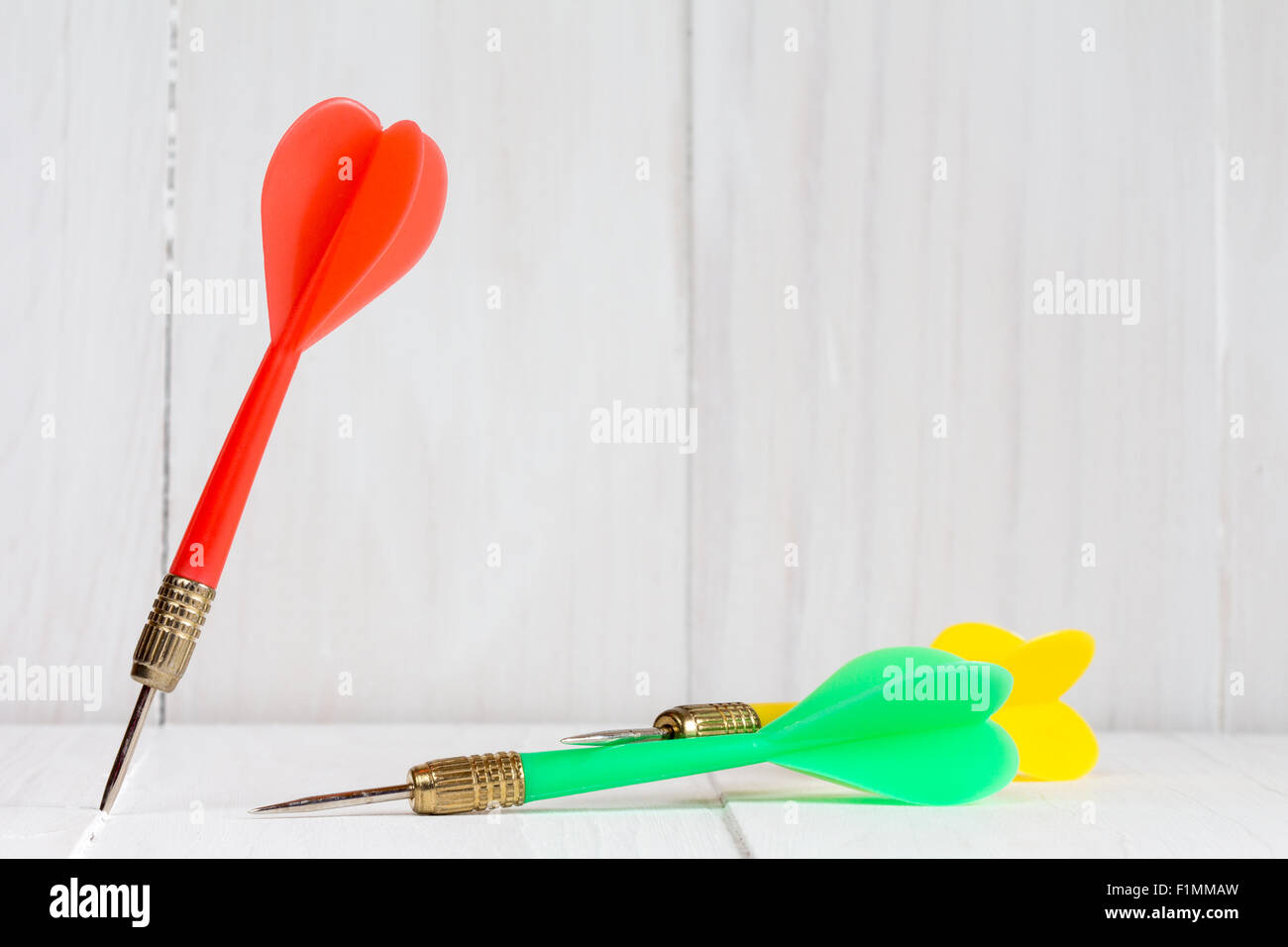 Three color darts on a white wooden background Stock Photo - Alamy