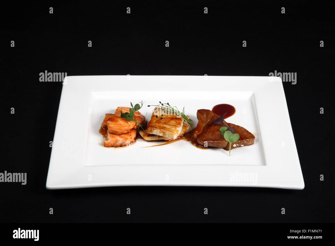 mixed fish grilled in white plate on a black background Stock Photo - Alamy