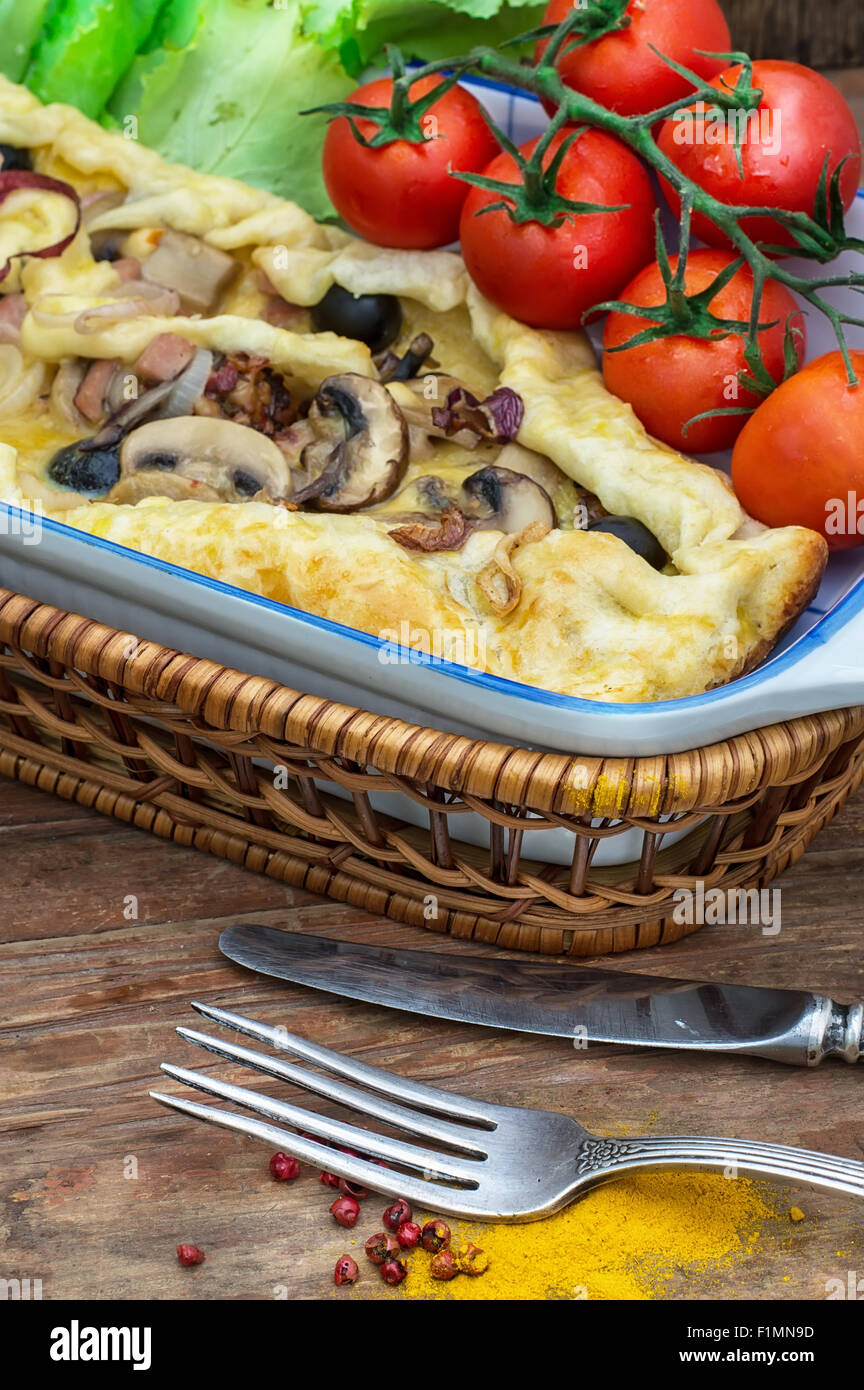 Pizza is of irregular shape elongated in length with fresh vegetables ...