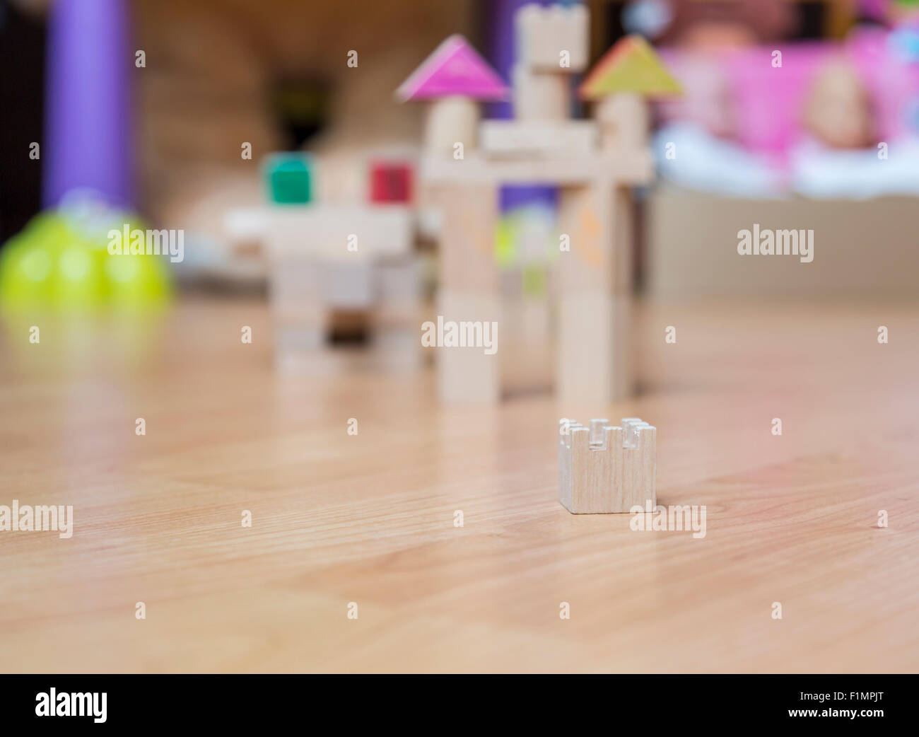 Wooden cube in front of a cubes construction on a floor in a kid's room ...