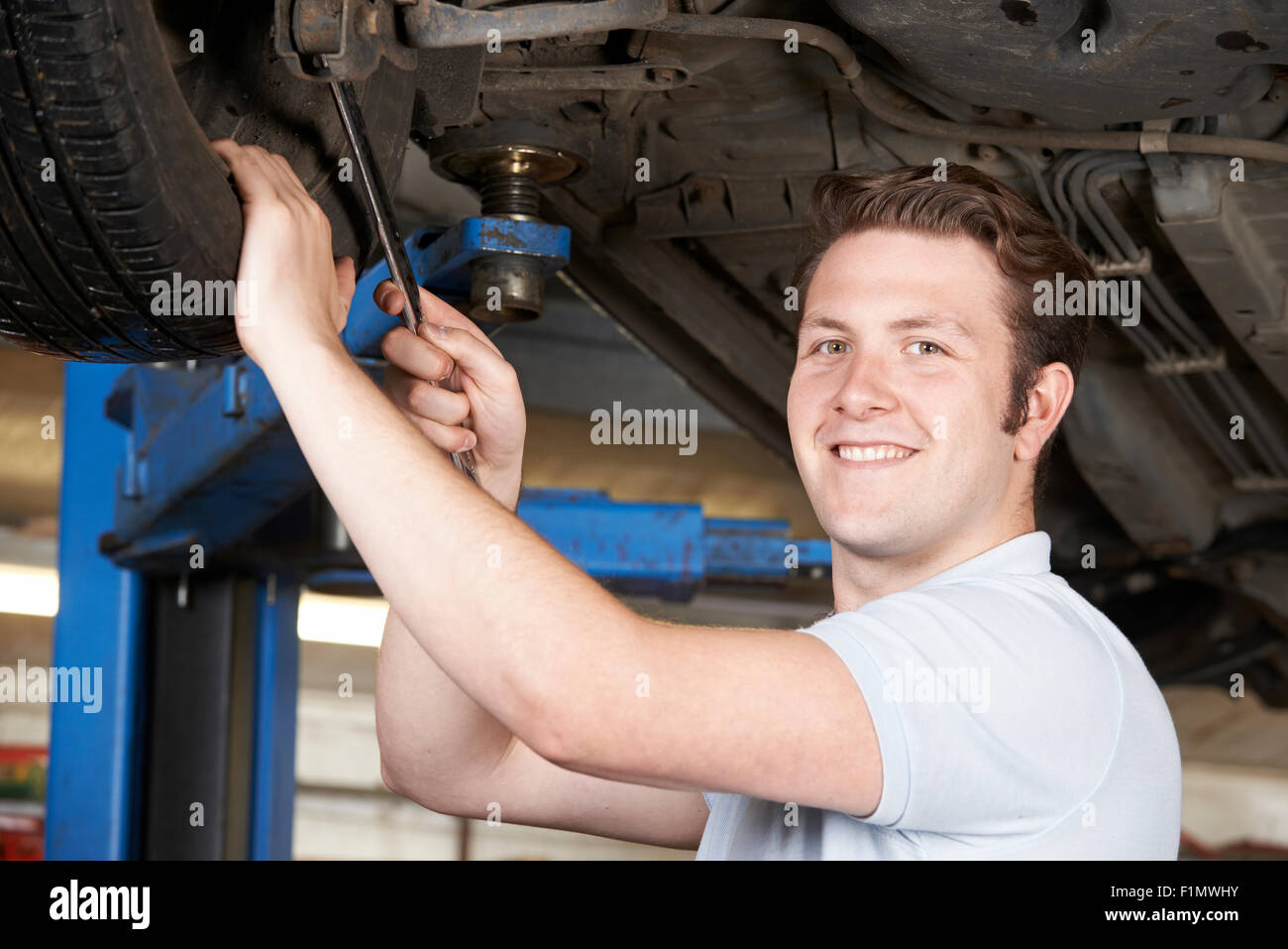 Portrait Of Mechanic Working On Wheel Underneath Car Stock Photo - Alamy