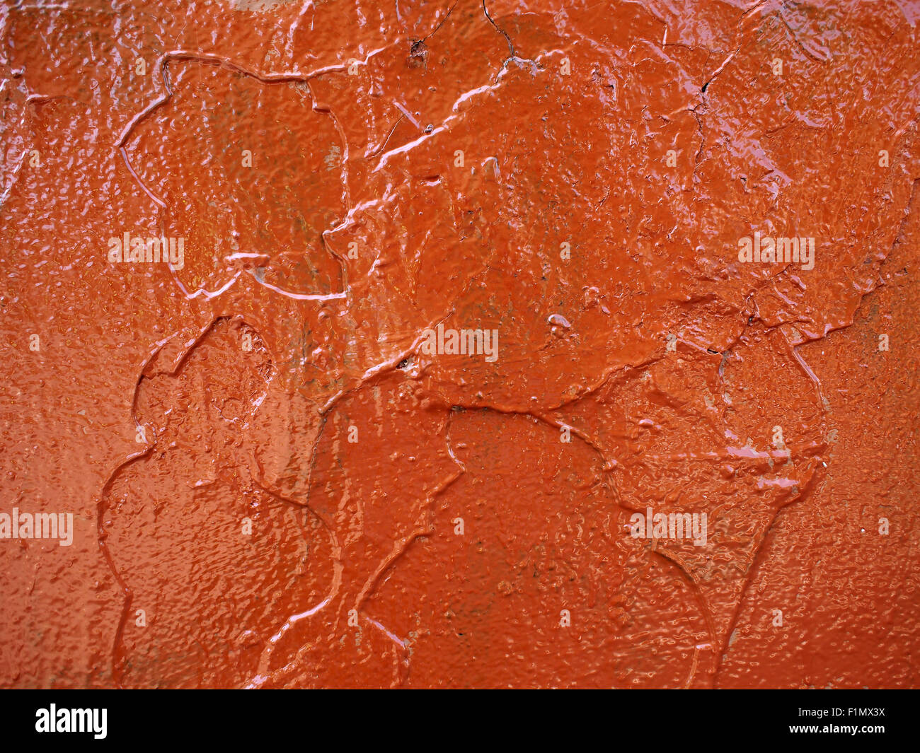 The thick and uneven layer of red paint on a wall closeup for use as ...