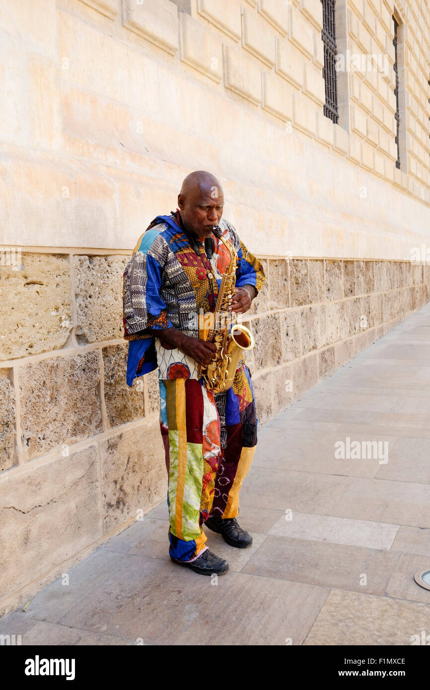 Colourful dressed african sax player, playing on street in Malaga ...