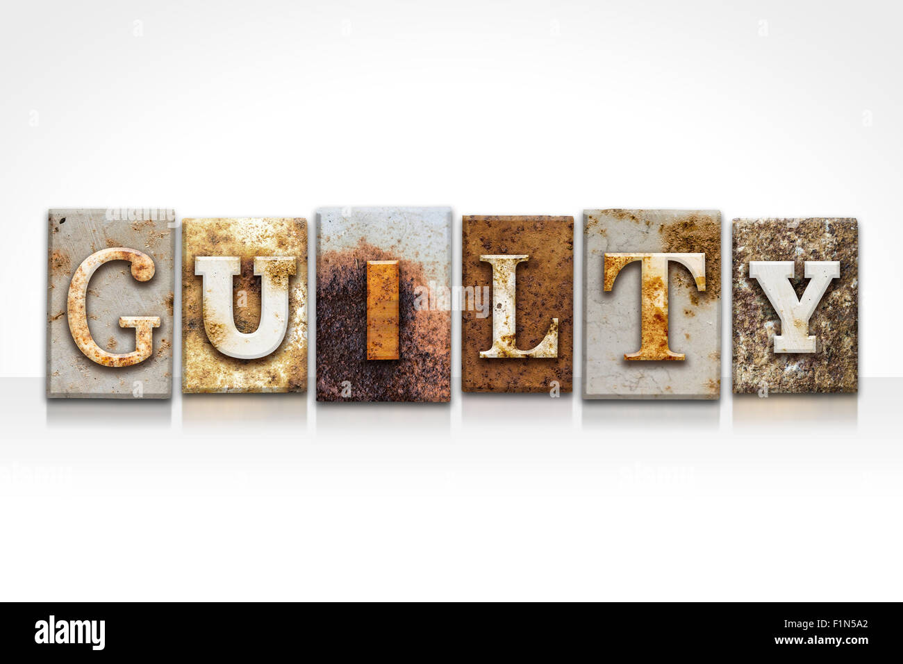 The word "GUILTY" written in rusty metal letterpress type isolated on a ...