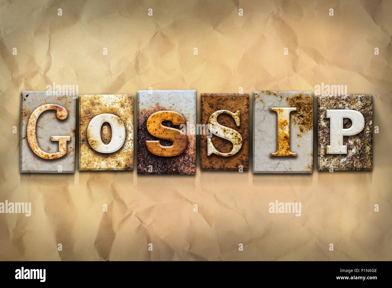The word "GOSSIP" written in rusty metal letterpress type on a crumbled ...