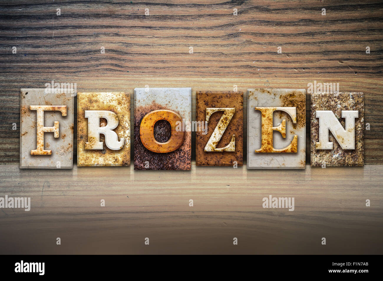 The word "FROZEN" written in rusty metal letterpress type sitting on a ...