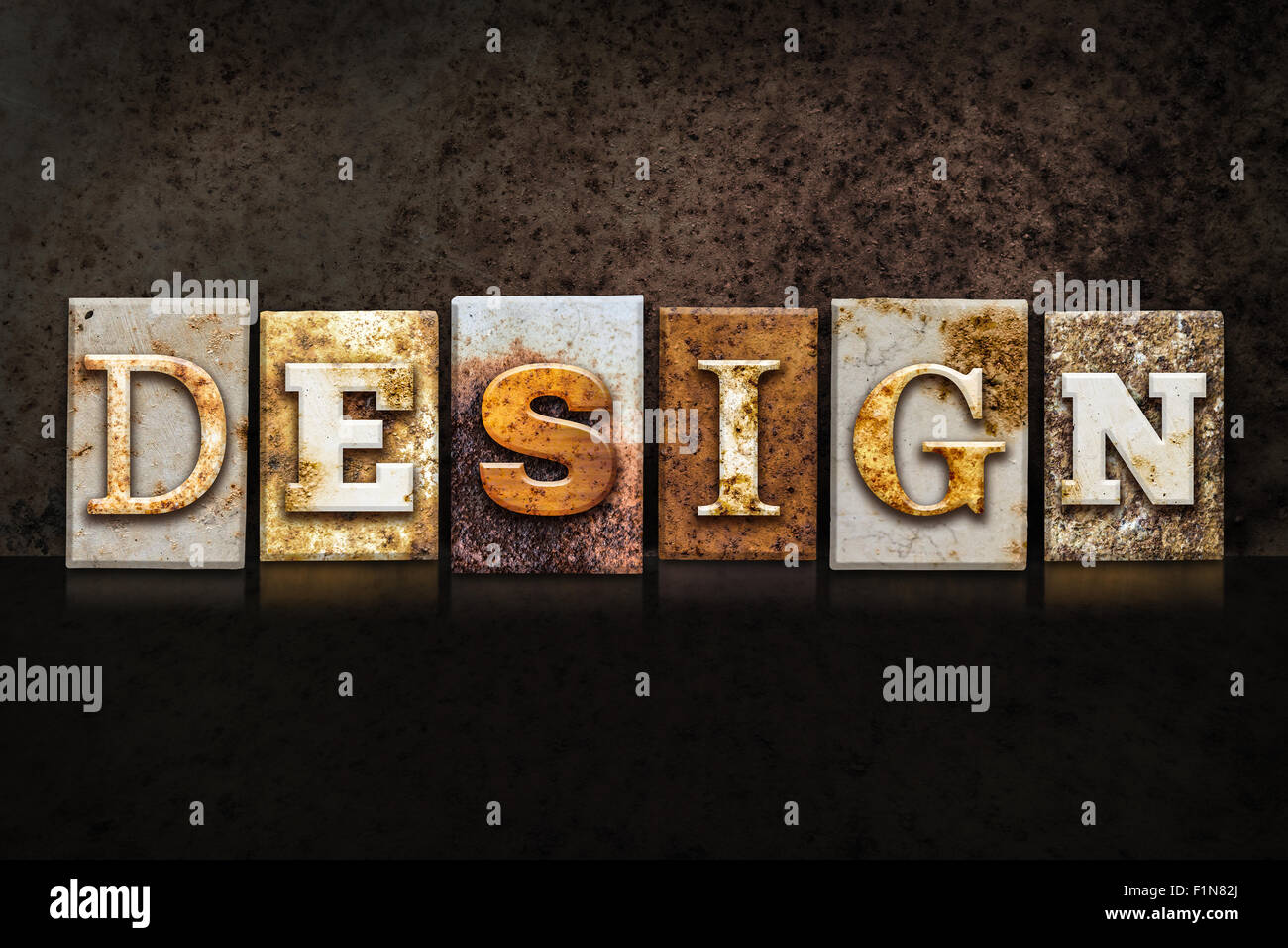 The word "DESIGN" written in rusty metal letterpress type on a dark ...