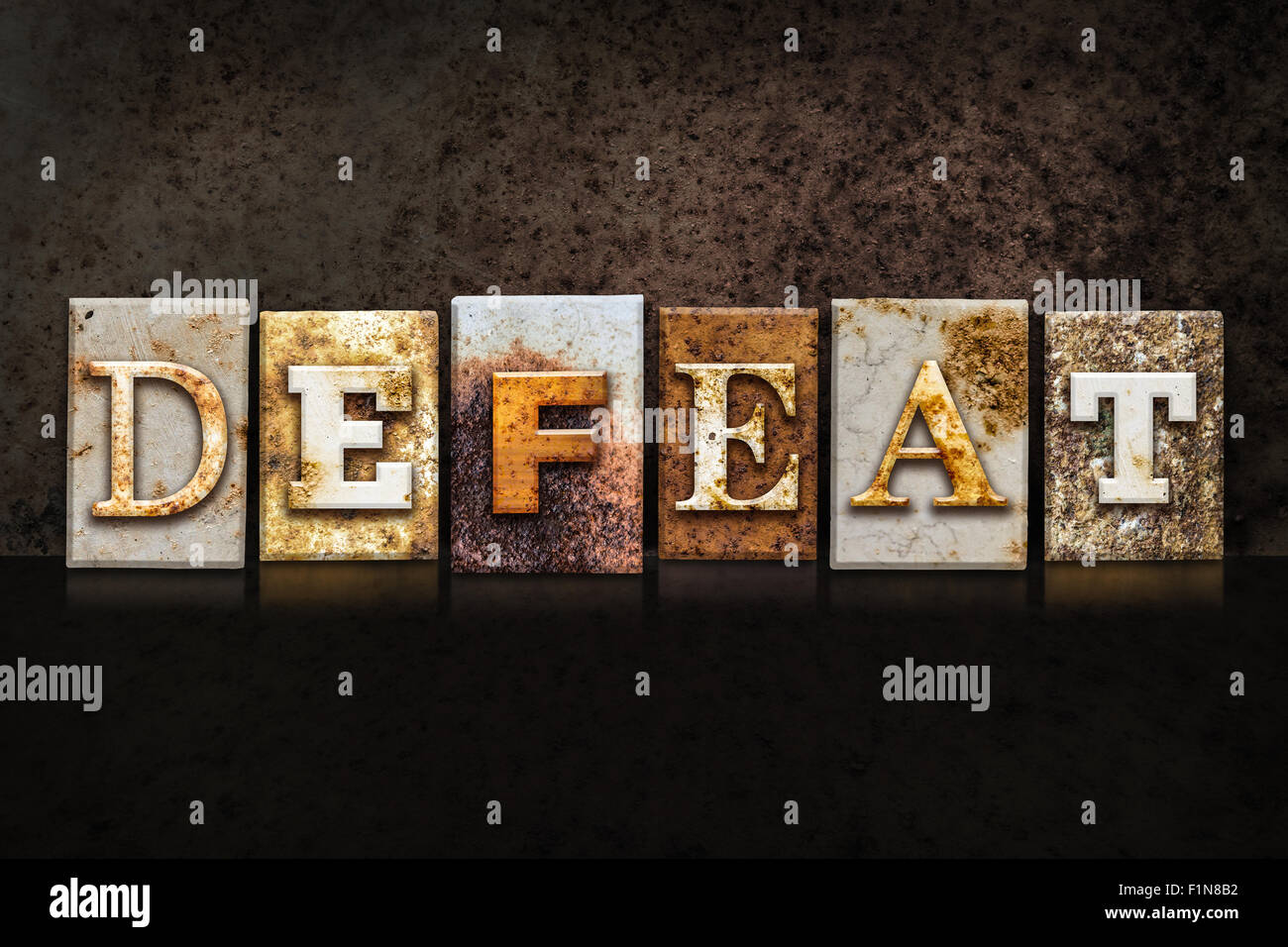 The word "DEFEAT" written in rusty metal letterpress type on a dark ...