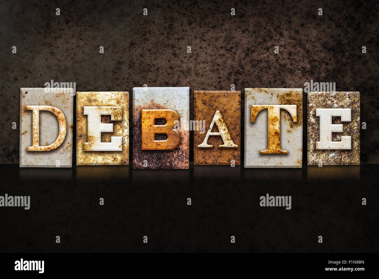 The word "DEBATE" written in rusty metal letterpress type on a dark ...