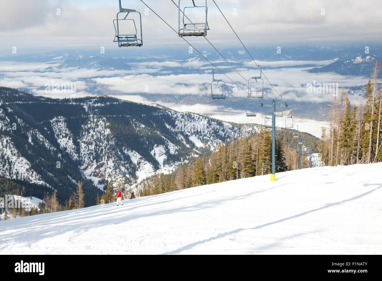 A chair lift for a winter ski resort goes up the side of a snowy ...