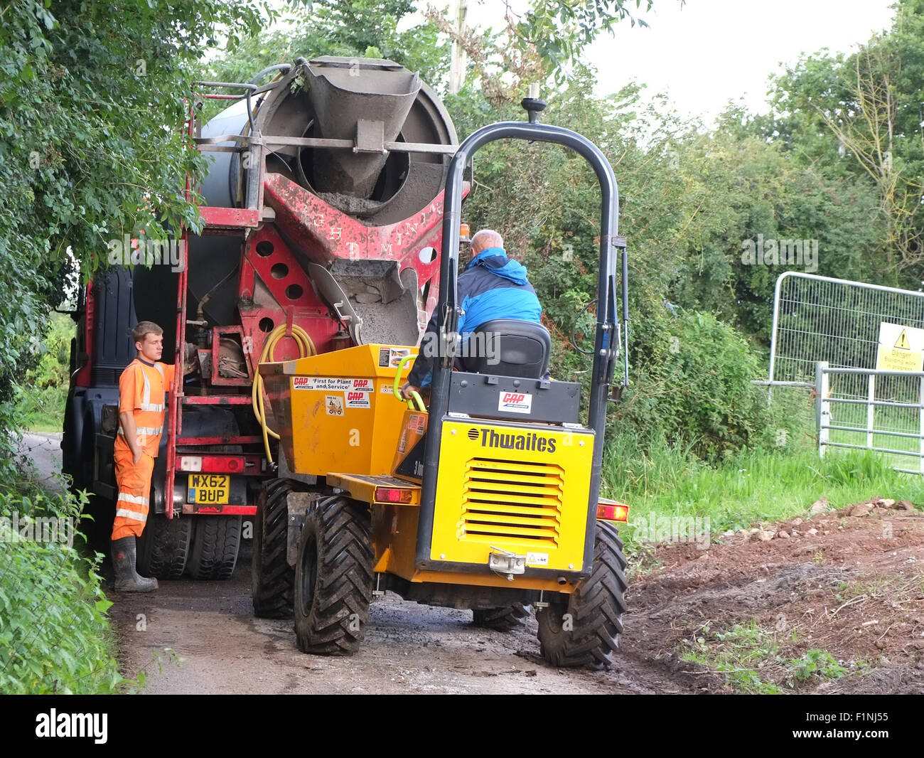 Unloading a concrete truck in a narrow country lane into a small ...