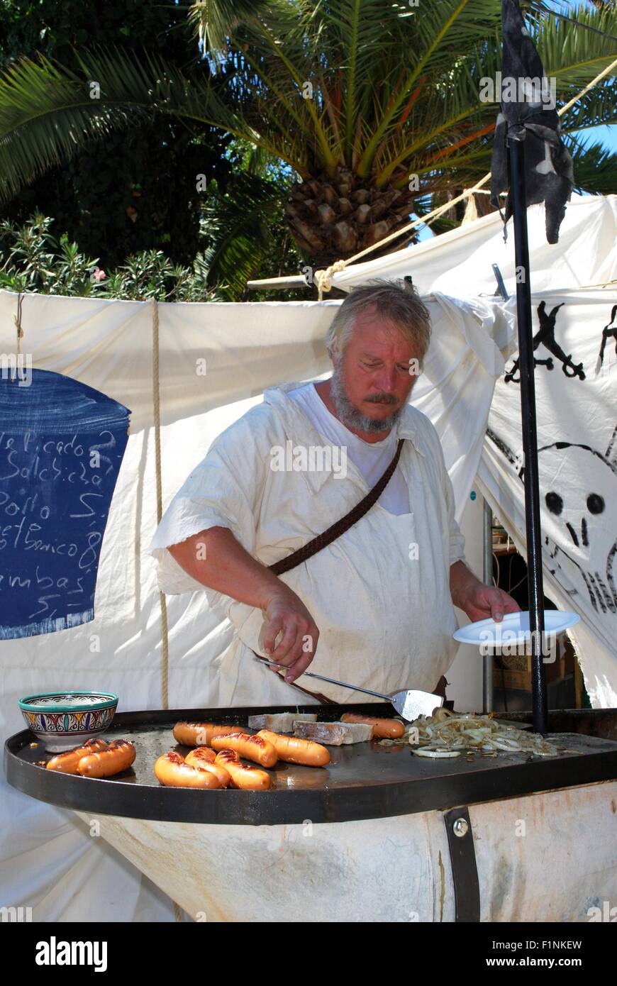 Chef cooking sausages and onions on a stall at the Medieval market ...