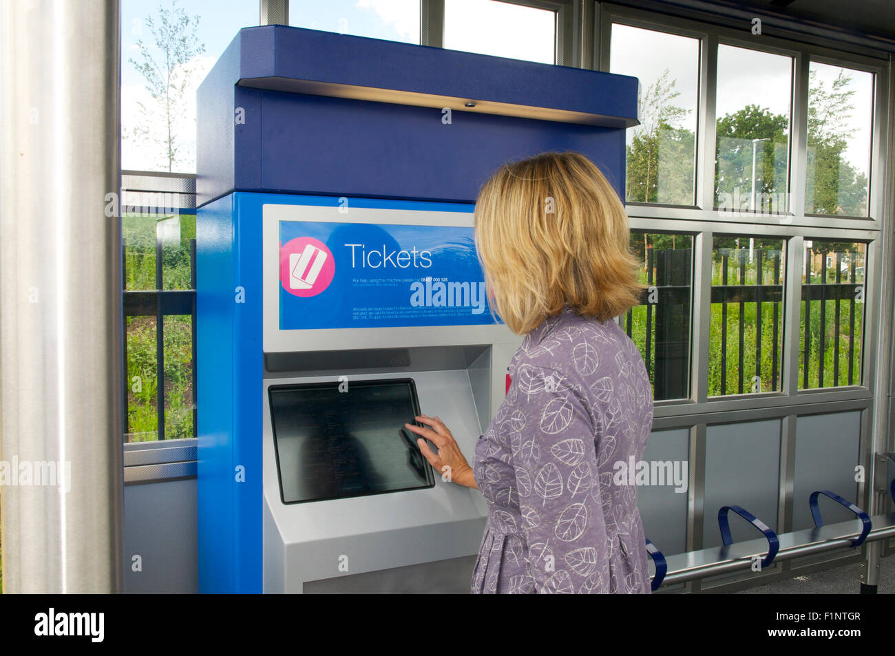 Woman buying rail ticket from a ticket machine at a station, UK Stock ...