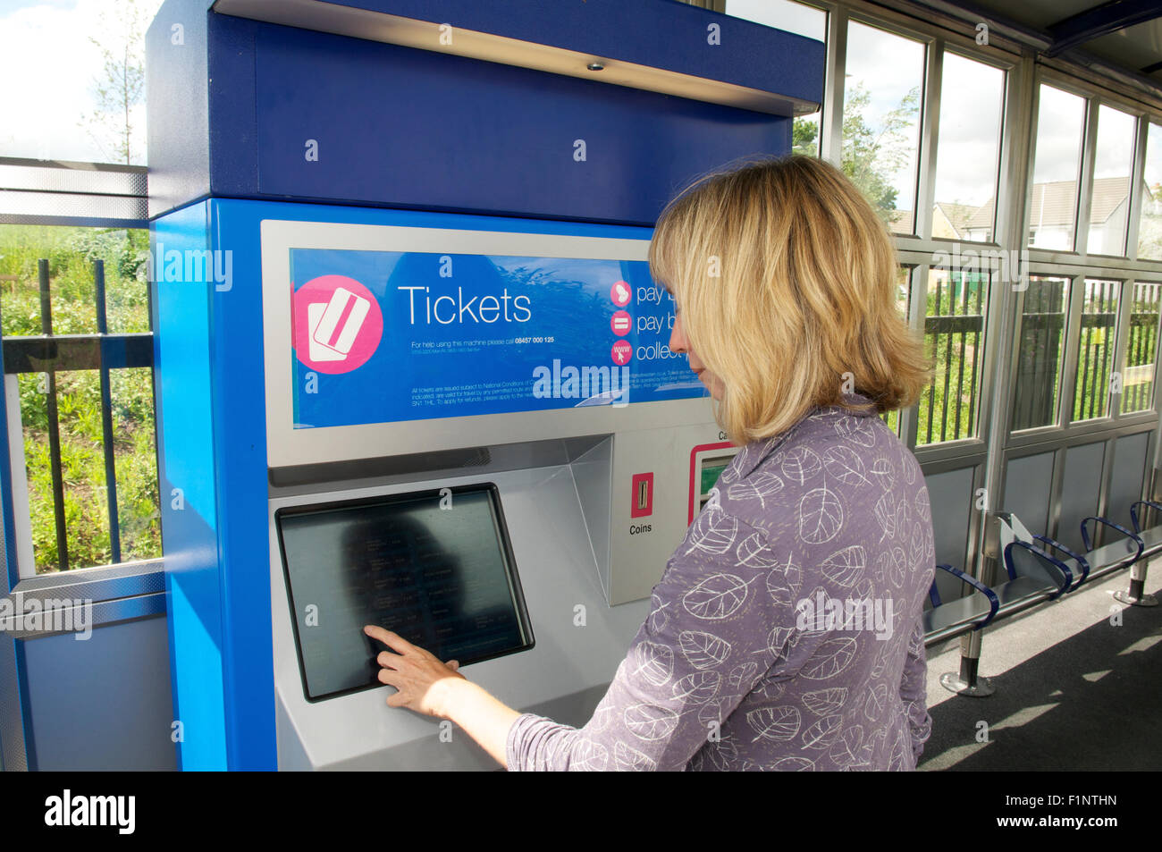 Woman buying rail ticket from a ticket machine at a station, UK Stock ...