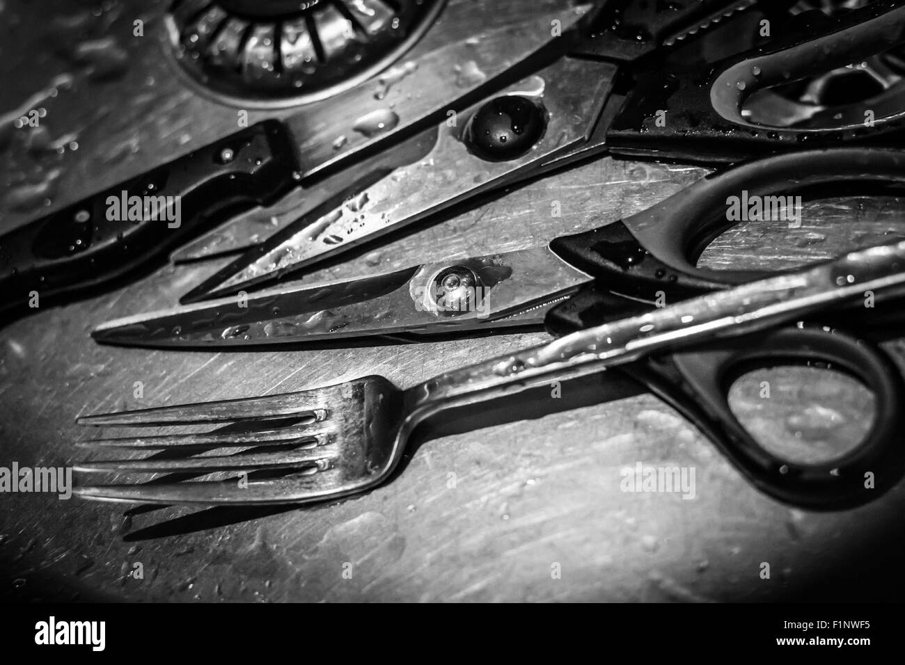 Group of four water splashed kitchen utensils resting in a metallic ...