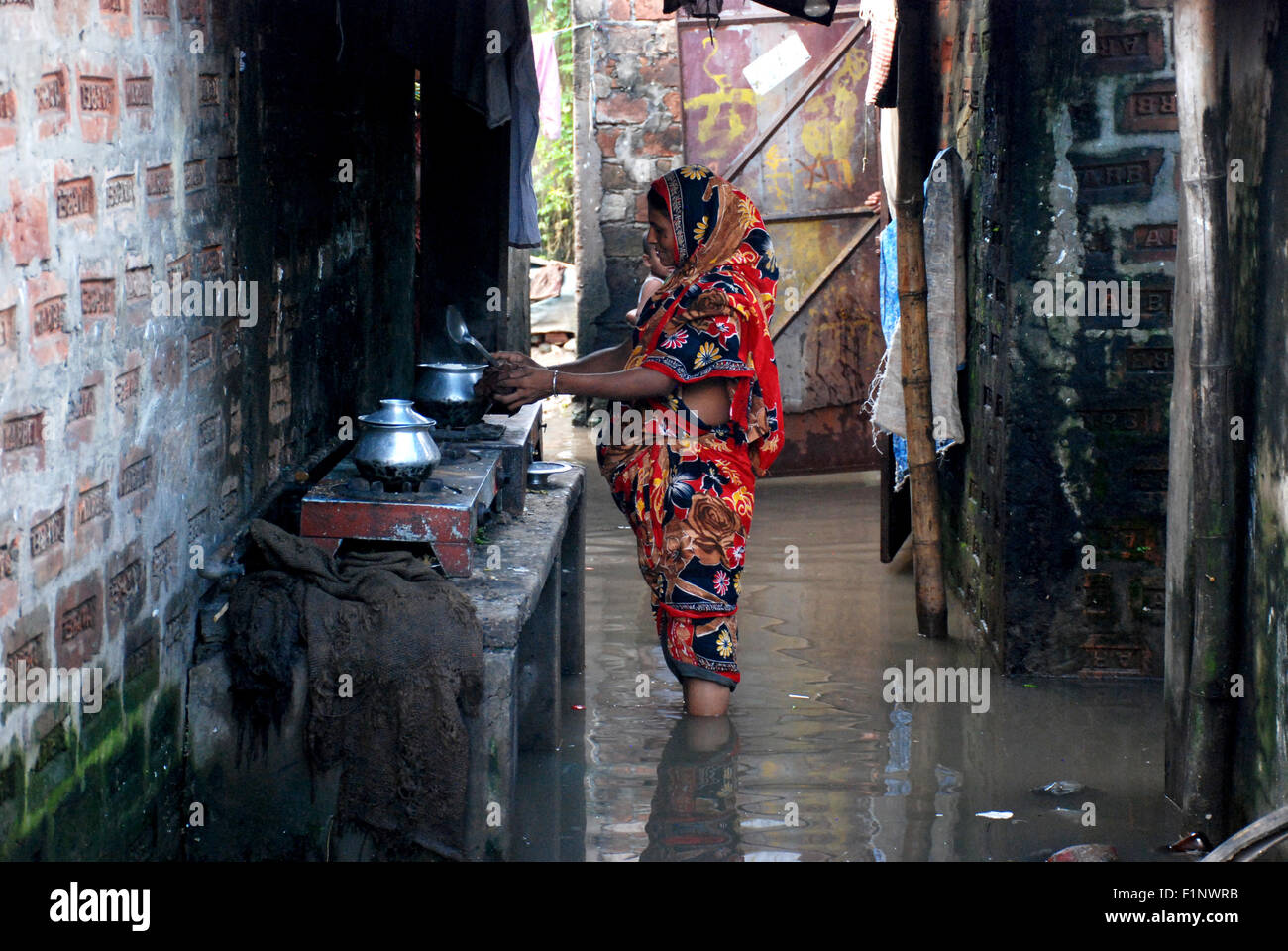 Flood-affected people standing on the dirty water while cooking their ...