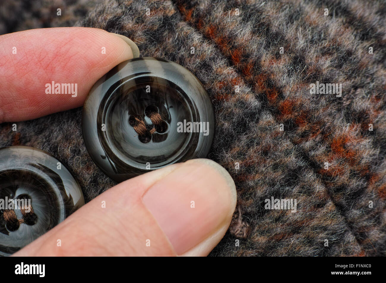 Human fingers holding button on clothing Stock Photo - Alamy