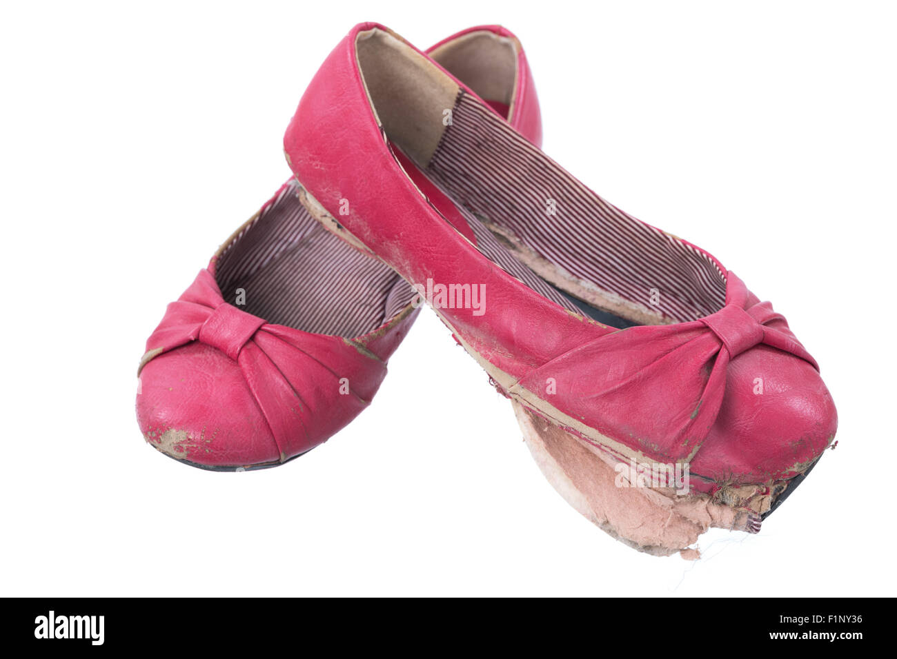 A pair of old, dirty and worn out red women's flats isolated on a white ...