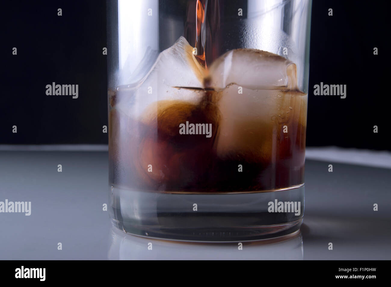 Rum being poured over vodka and ice in clear glass Stock Photo - Alamy