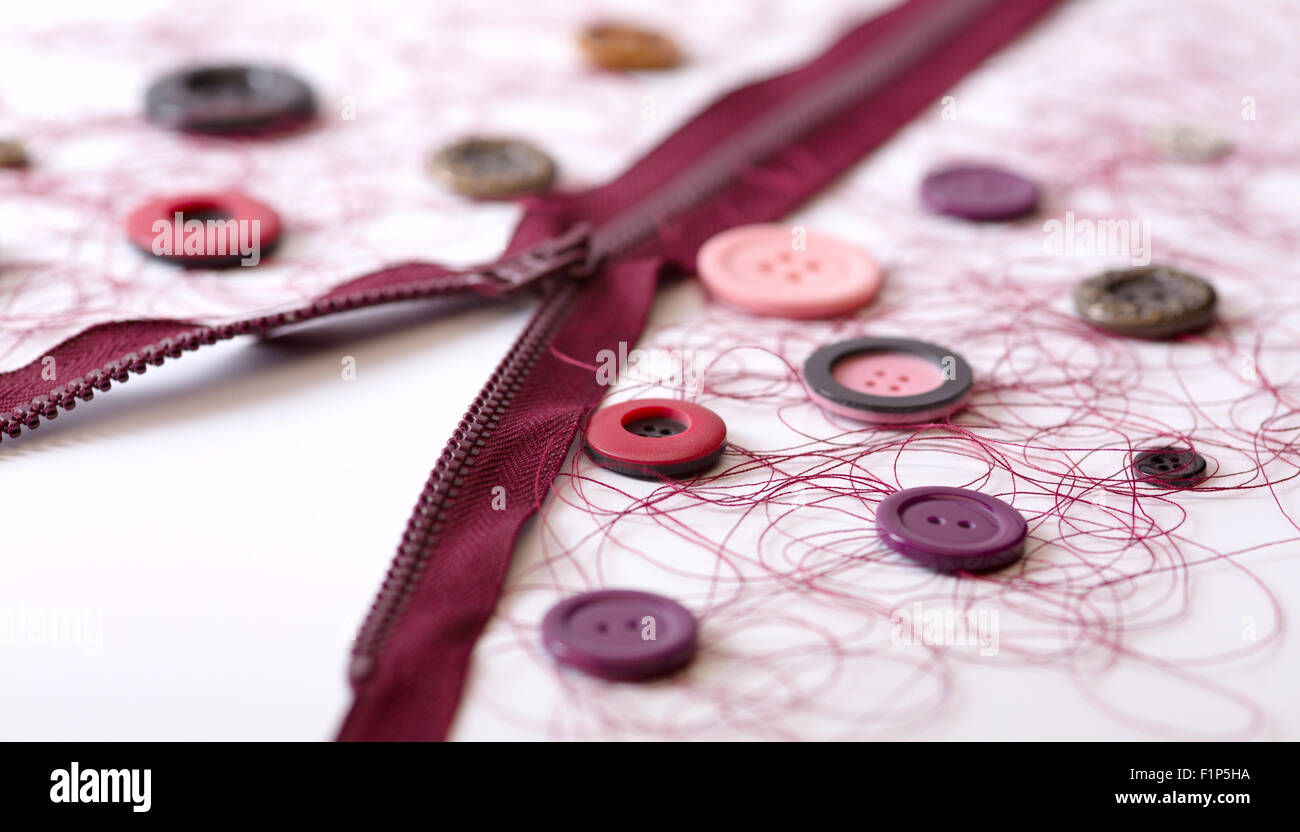 maroon zipper, scattered threads and buttons in different shapes and ...