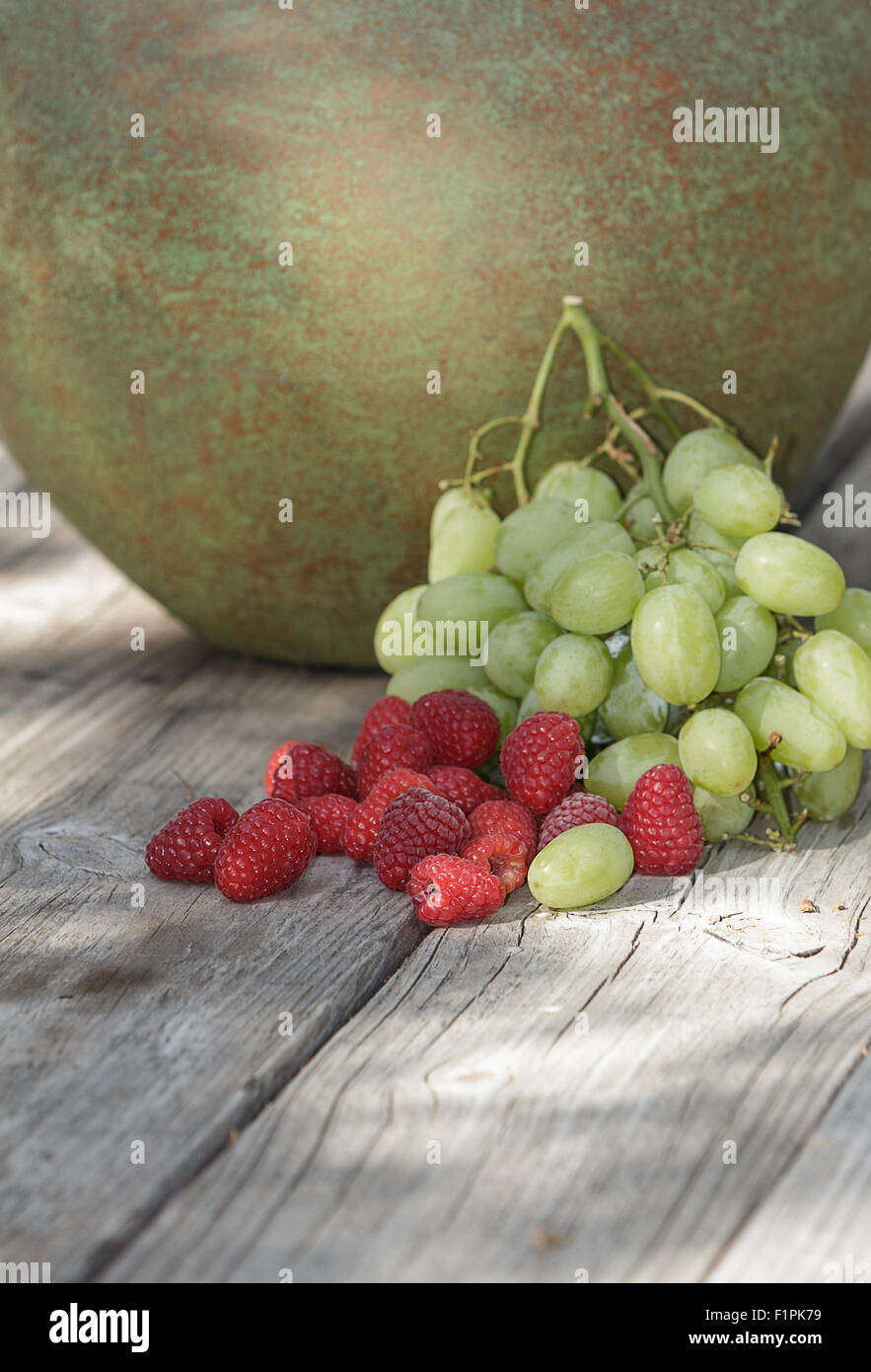 Green grapes and raspberries on a rustic wood table in summer Stock ...