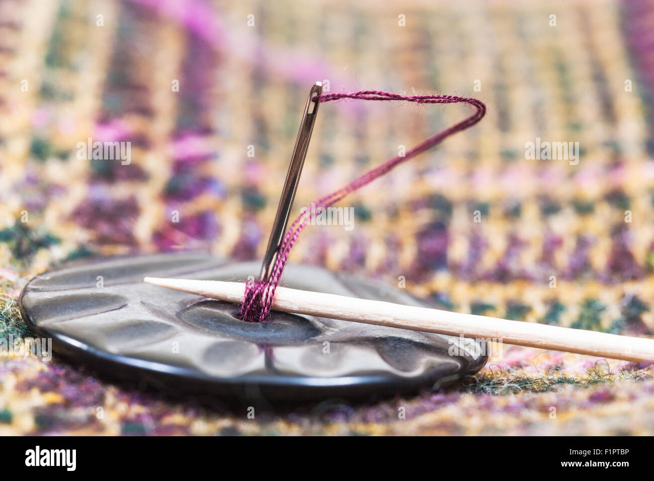 attaching of button to woolen textile with stick by needle close up ...