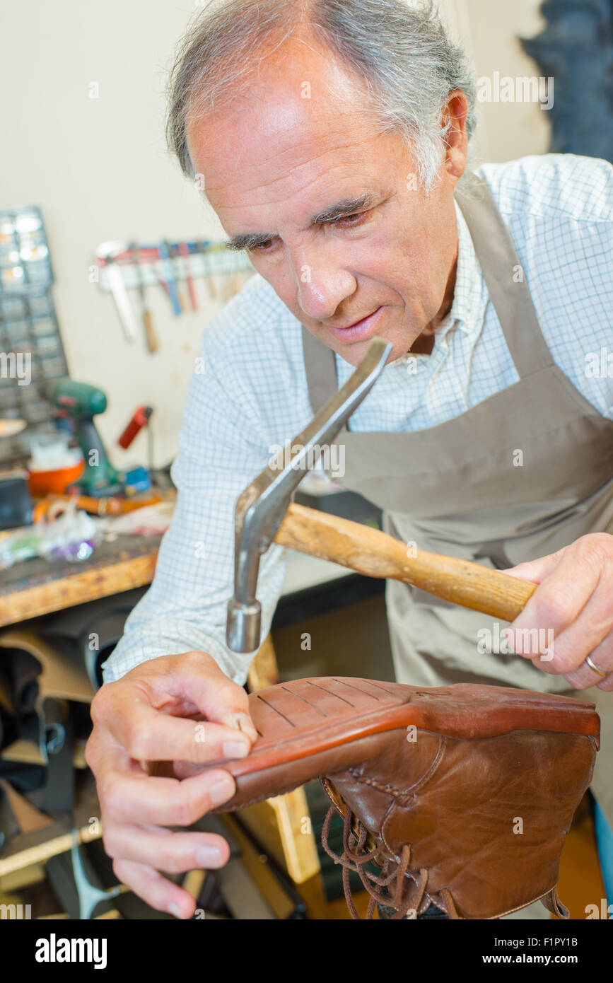Cobbler using a hammer Stock Photo - Alamy