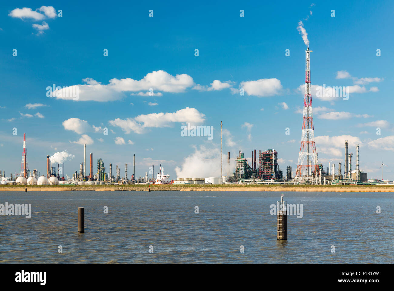 A refinery with tall flare stack in the port of Antwerp, Belgium with ...
