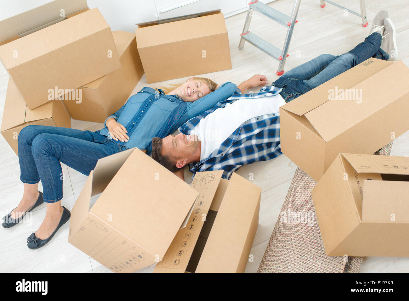 Exhausted couple laying amongst cardboard boxes Stock Photo - Alamy
