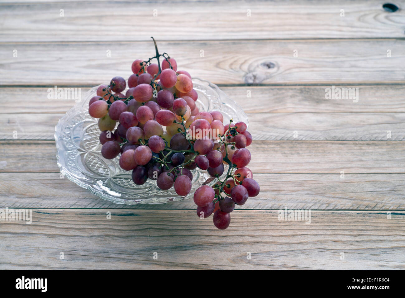Bunch of grapes on a glass tray on wooden table Stock Photo - Alamy