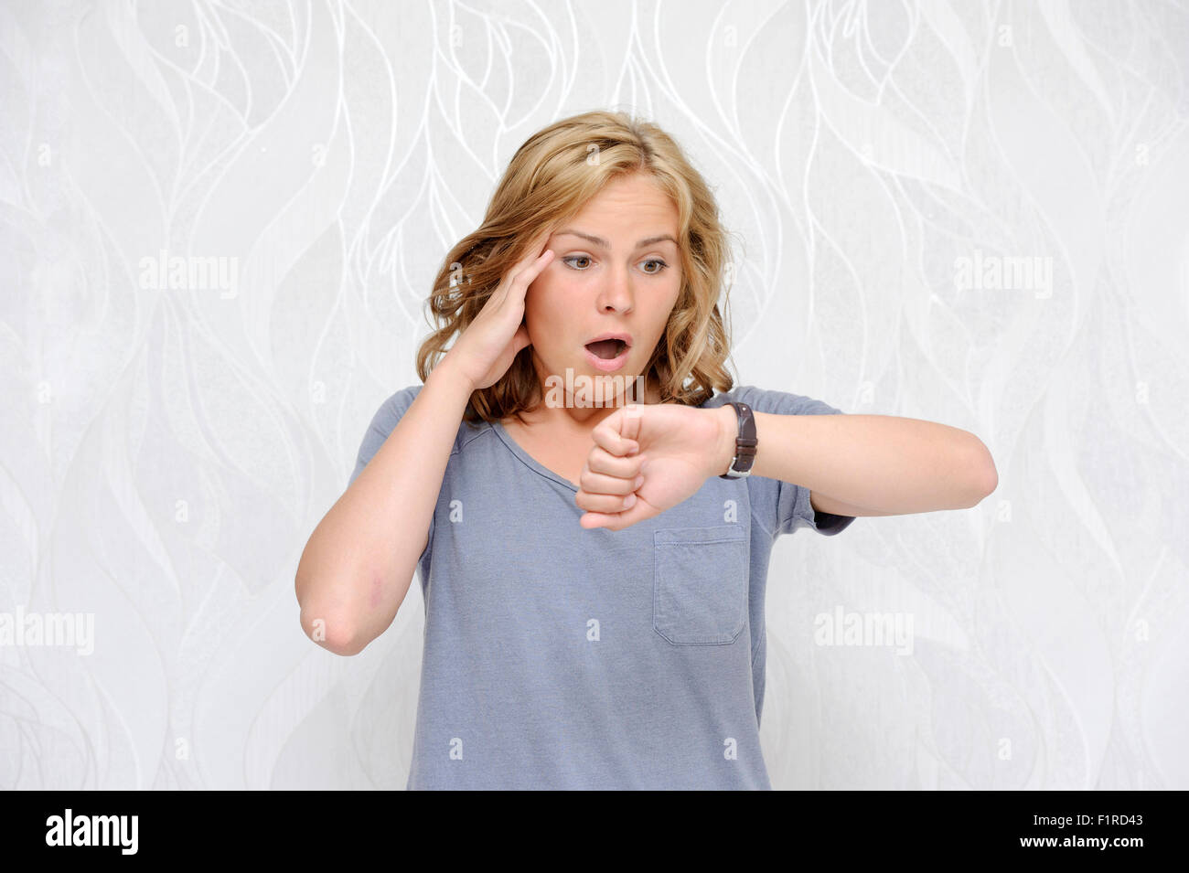 Young woman looking at her watch being late Stock Photo - Alamy