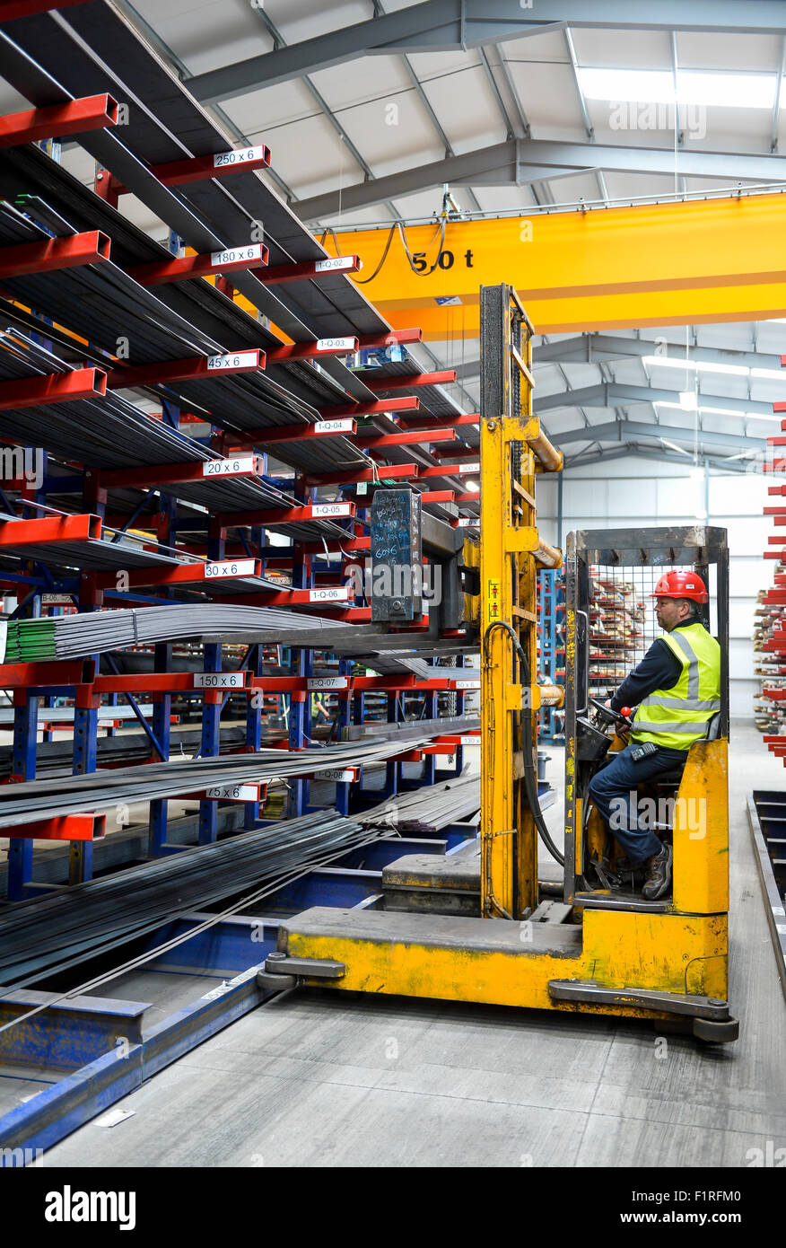 Steel warehouse racking side loading forklift Stock Photo - Alamy