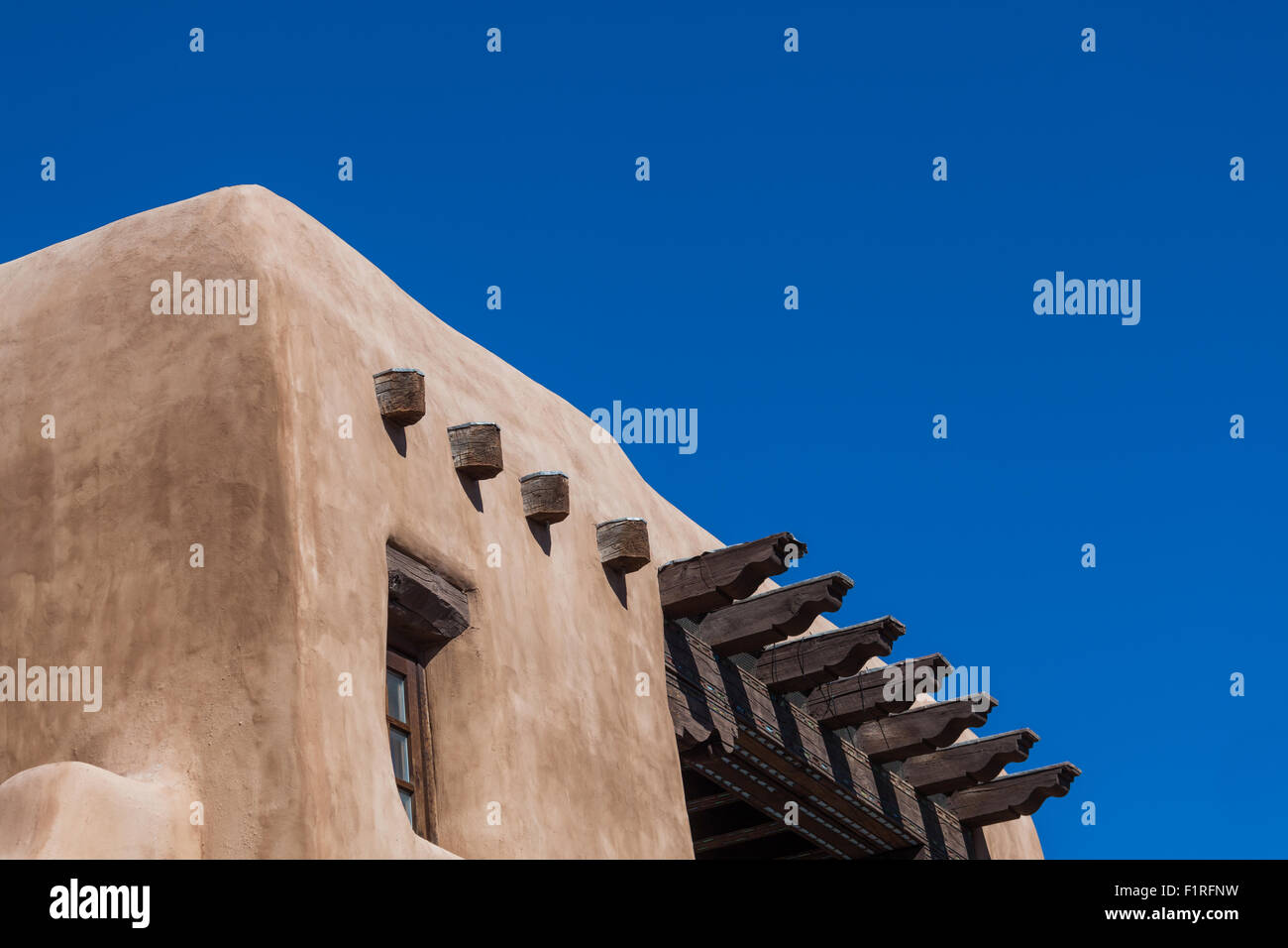 Scalloped beams with painted details adorn a adobe building done in ...