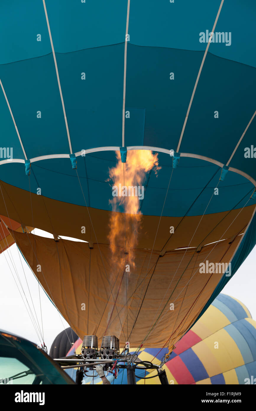 Close up of a hot air balloon flame inflating a blue balloon with other ...
