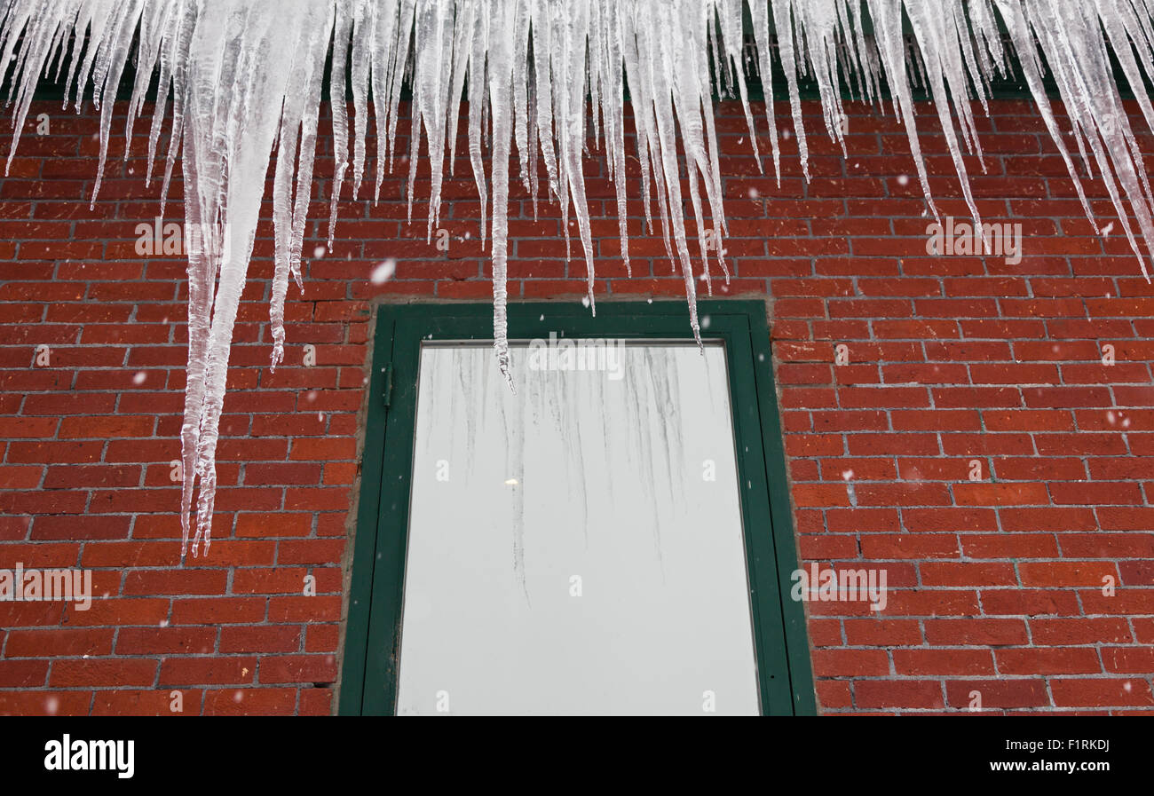 Long delicate fingers of ice hang from a gutter atop a red brick ...