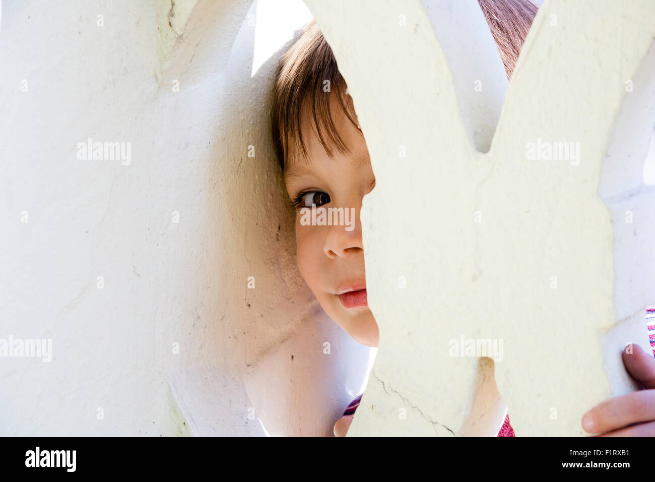 Caucasian child, boy, 3-4 year old, looking through gap in yellow stone ...