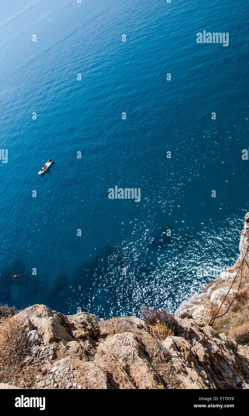 Top view of a deep blue sea and rocks of the coast. A little boat ...