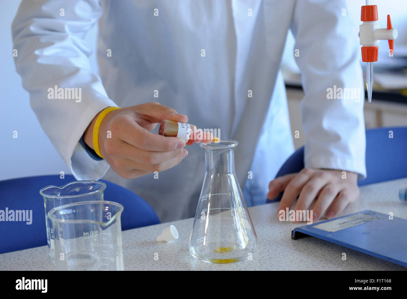 Science student adding chemical to a mixing flask Stock Photo - Alamy
