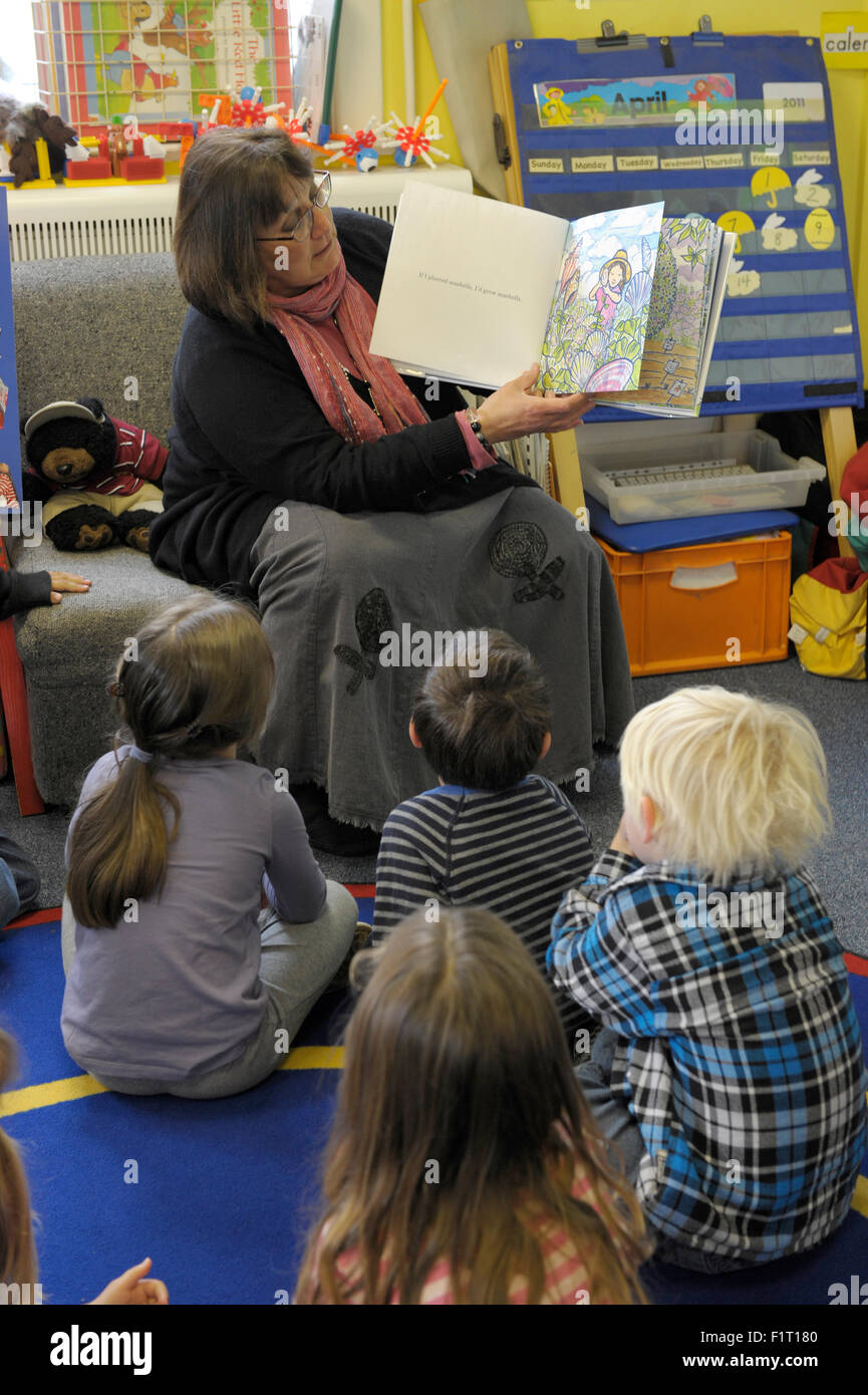Teacher showing story telling picture book to primary school children ...