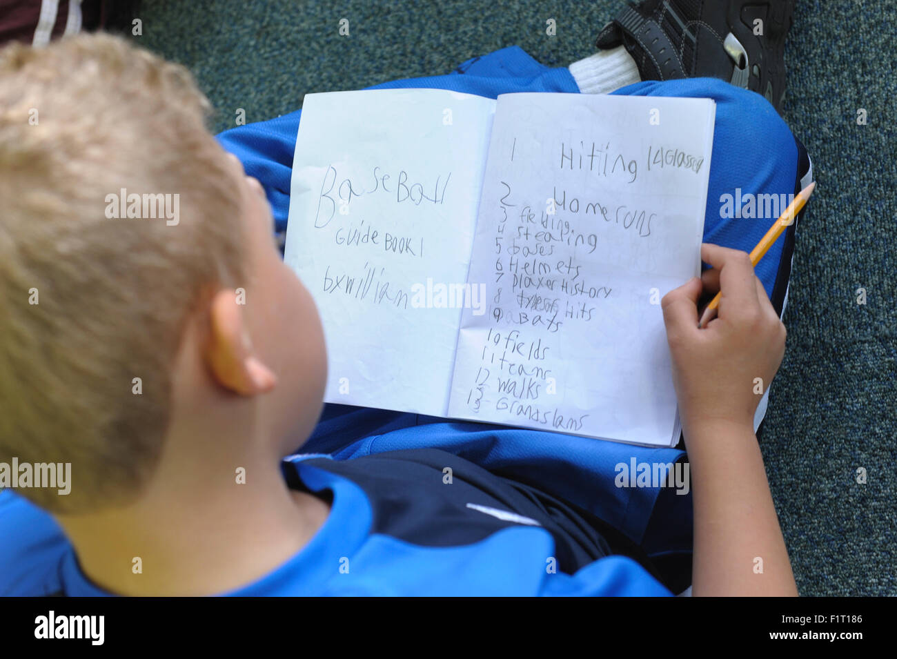 Primary school child sitting on classroom floor with written work Stock ...