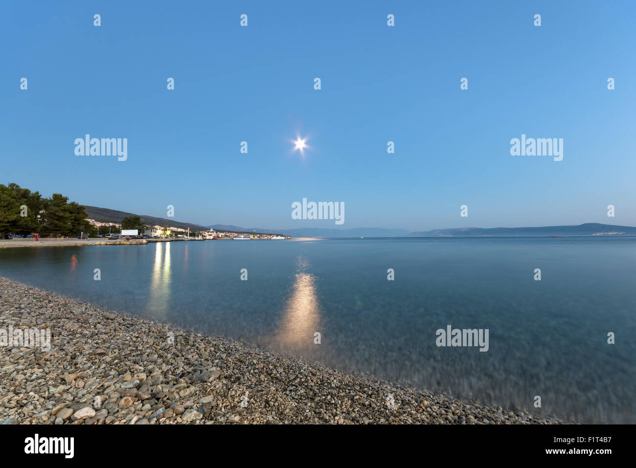Small pebble beach on Adriatic sea at night with Crikvenica town in the ...