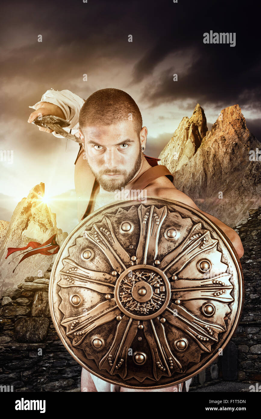 Gladiator or warrior posing with shield and sword outdoors ready for ...